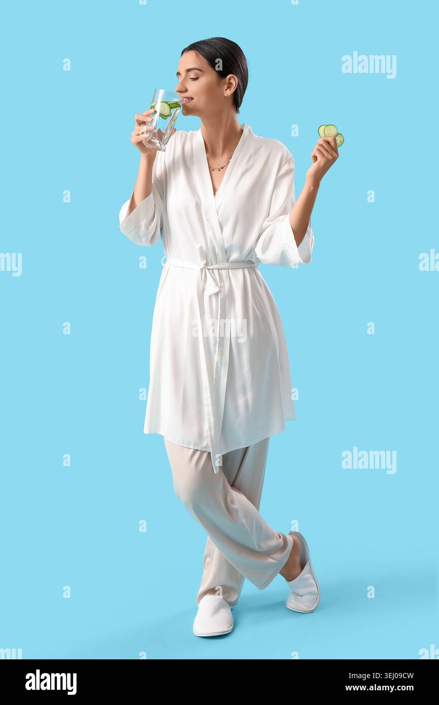Young woman drinking cucumber water on blue background Stock Photo - Alamy