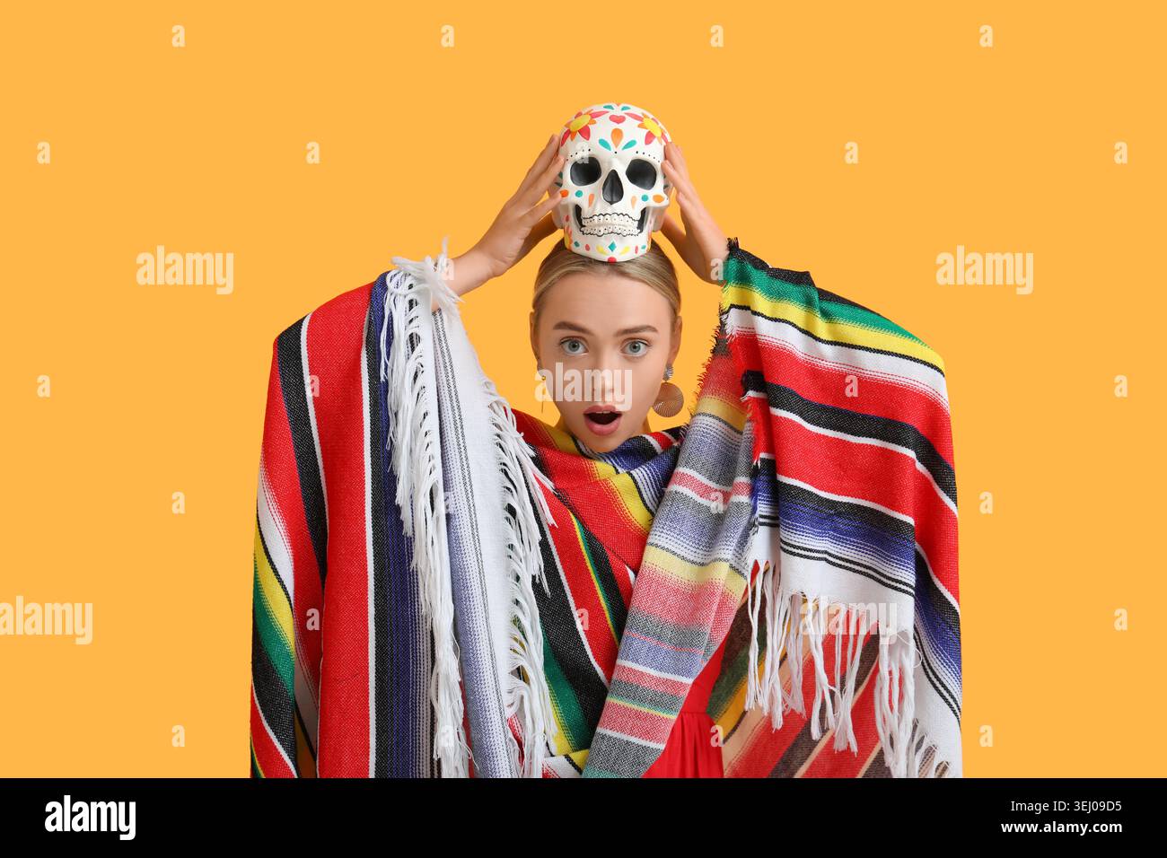 Pretty young woman in poncho with painted human skull on orange ...