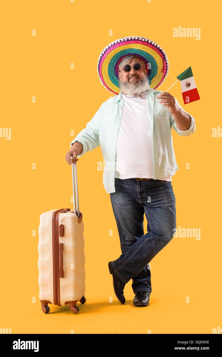 Mature man in sombrero hat with Mexican flag and suitcase on yellow ...