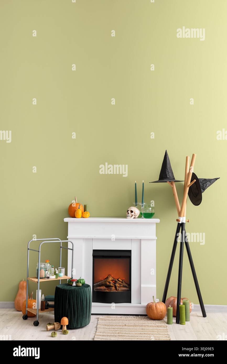White fireplace with Halloween pumpkins and decorations near green wall ...