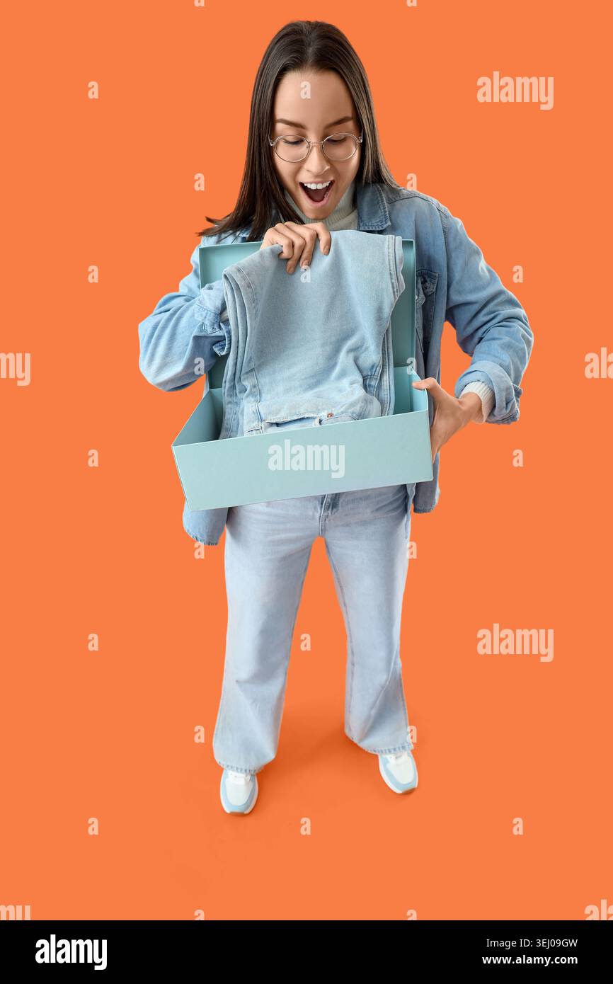 Female seller with jeans in box on orange background Stock Photo - Alamy