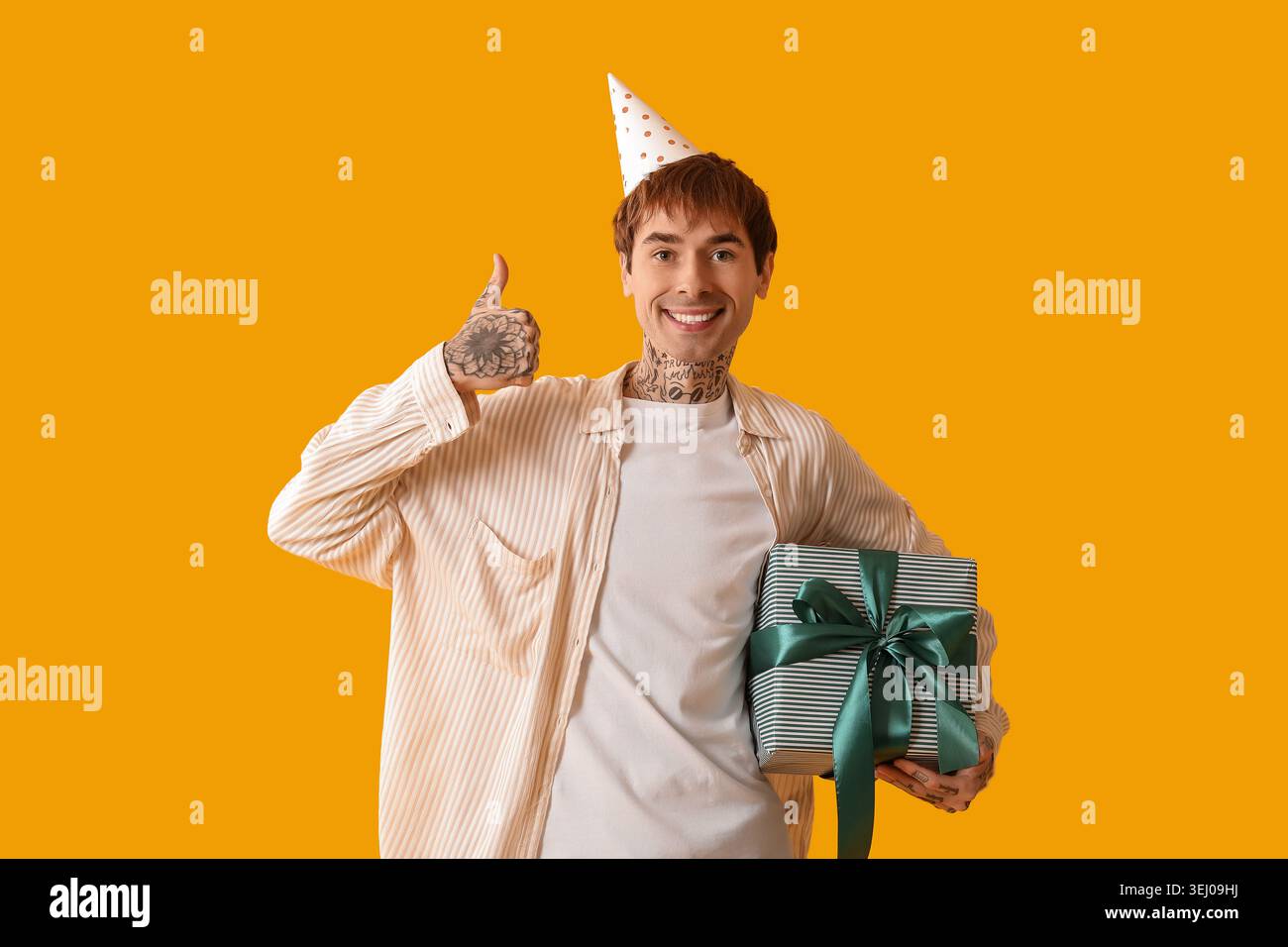 Young man in party hat with gift box celebrating Birthday and showing ...