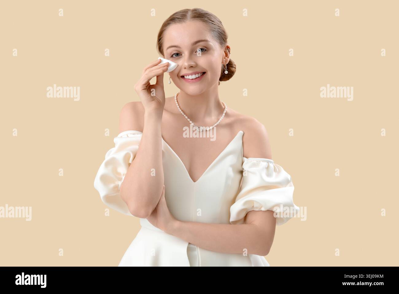 Young woman removing makeup with cotton pad on beige background Stock ...