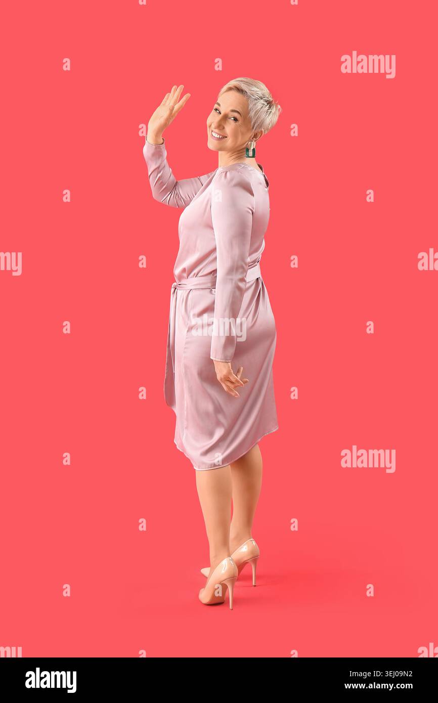 Stylish mature woman waving hand on red background Stock Photo - Alamy