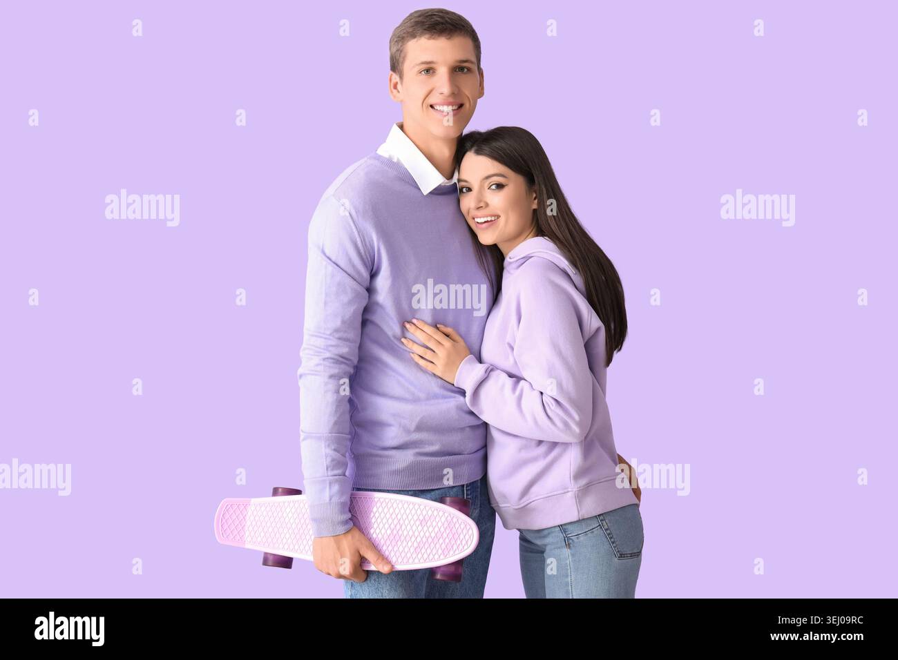 Happy young couple with skateboard hugging on lilac background Stock ...