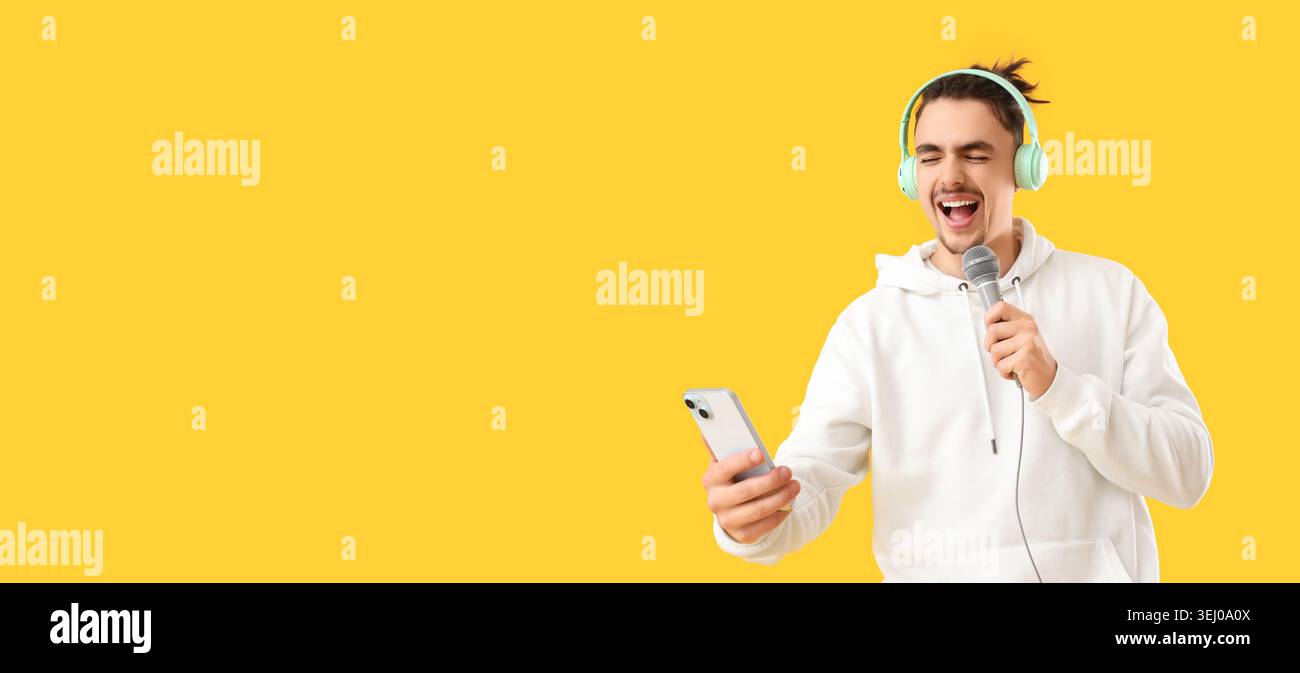Young man in headphones, with microphone and mobile phone singing on ...