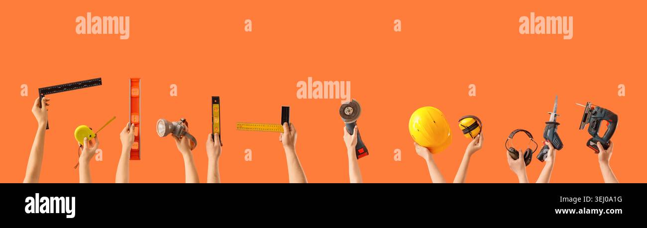 Hands holding construction tools on orange background Stock Photo - Alamy