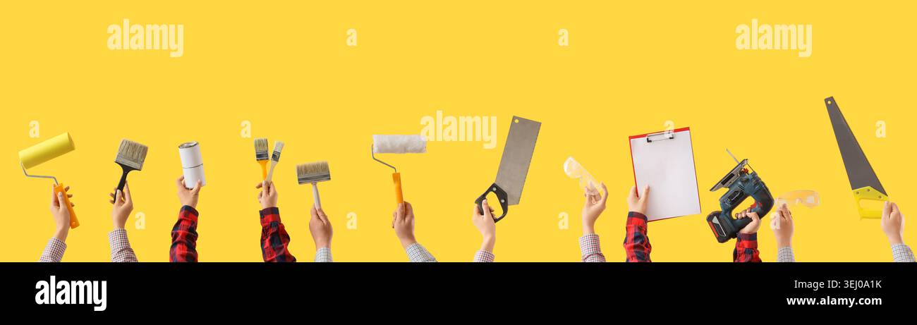 Hands holding construction tools and clipboard on yellow background ...