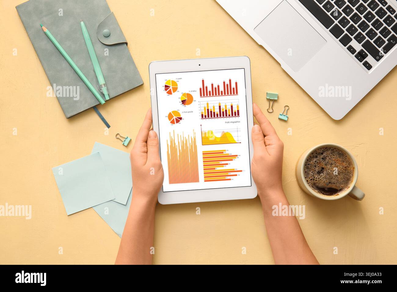Hands holding tablet computer with business charts on screen against ...