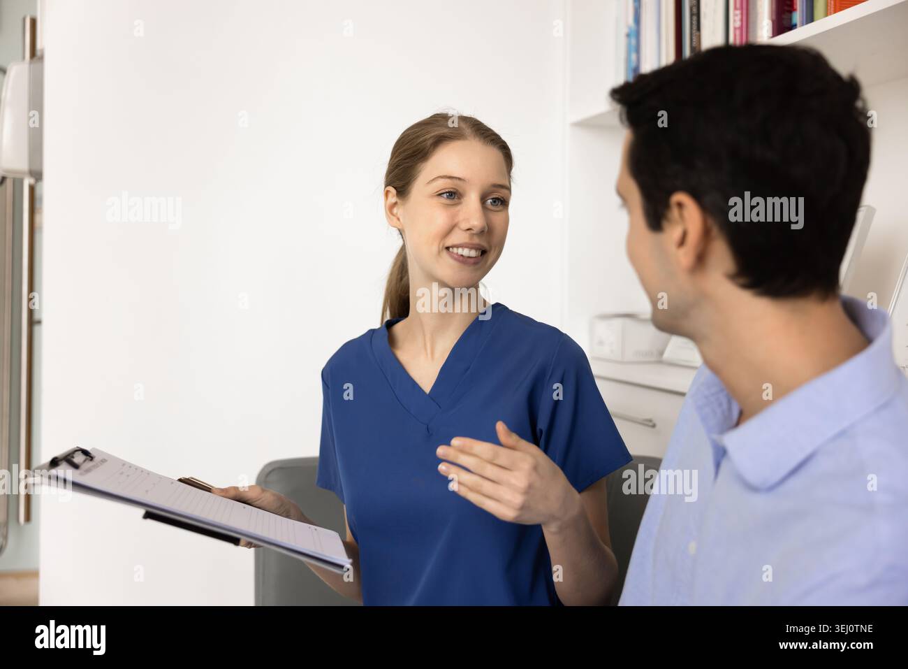 Smiling young adult female nurse holding clipboard with medical consent ...