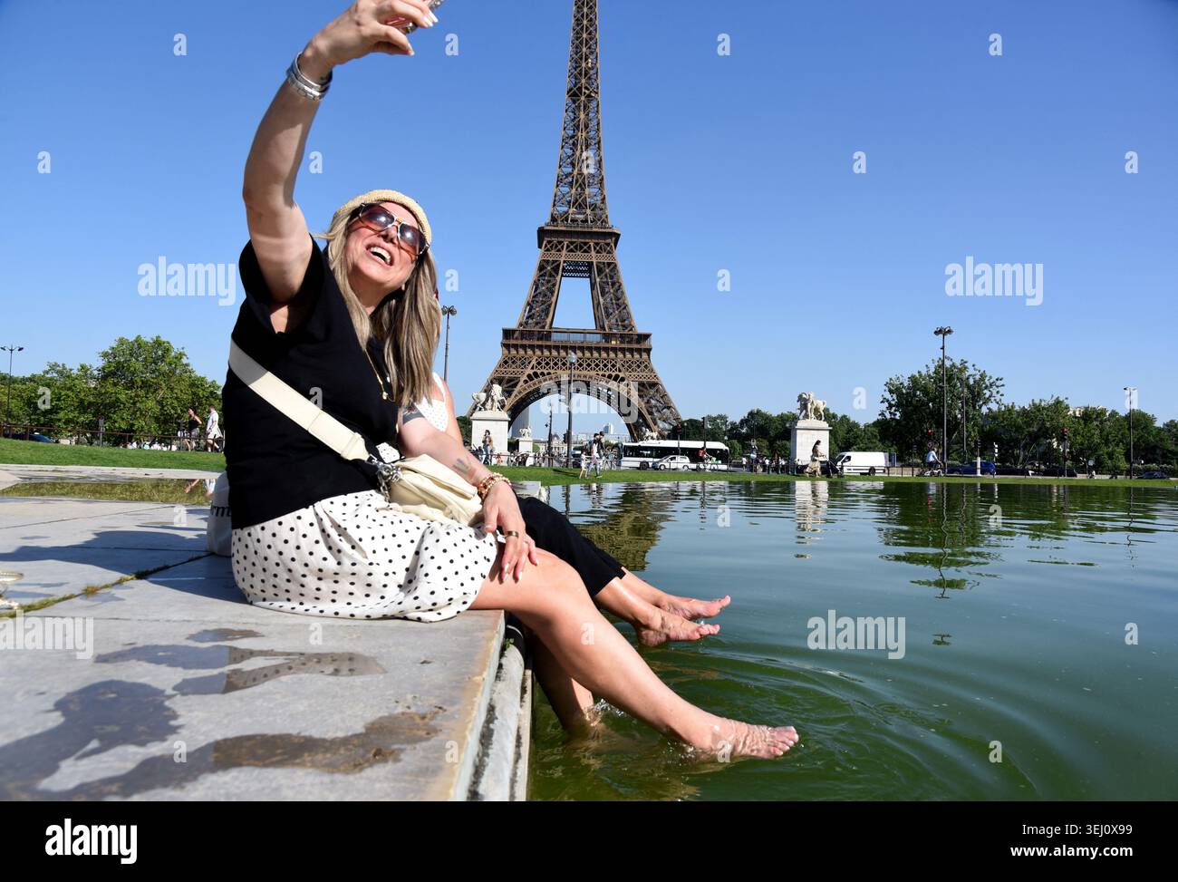 Tourists and Parisians cool themselves at the Eiffel Tower as a heat ...