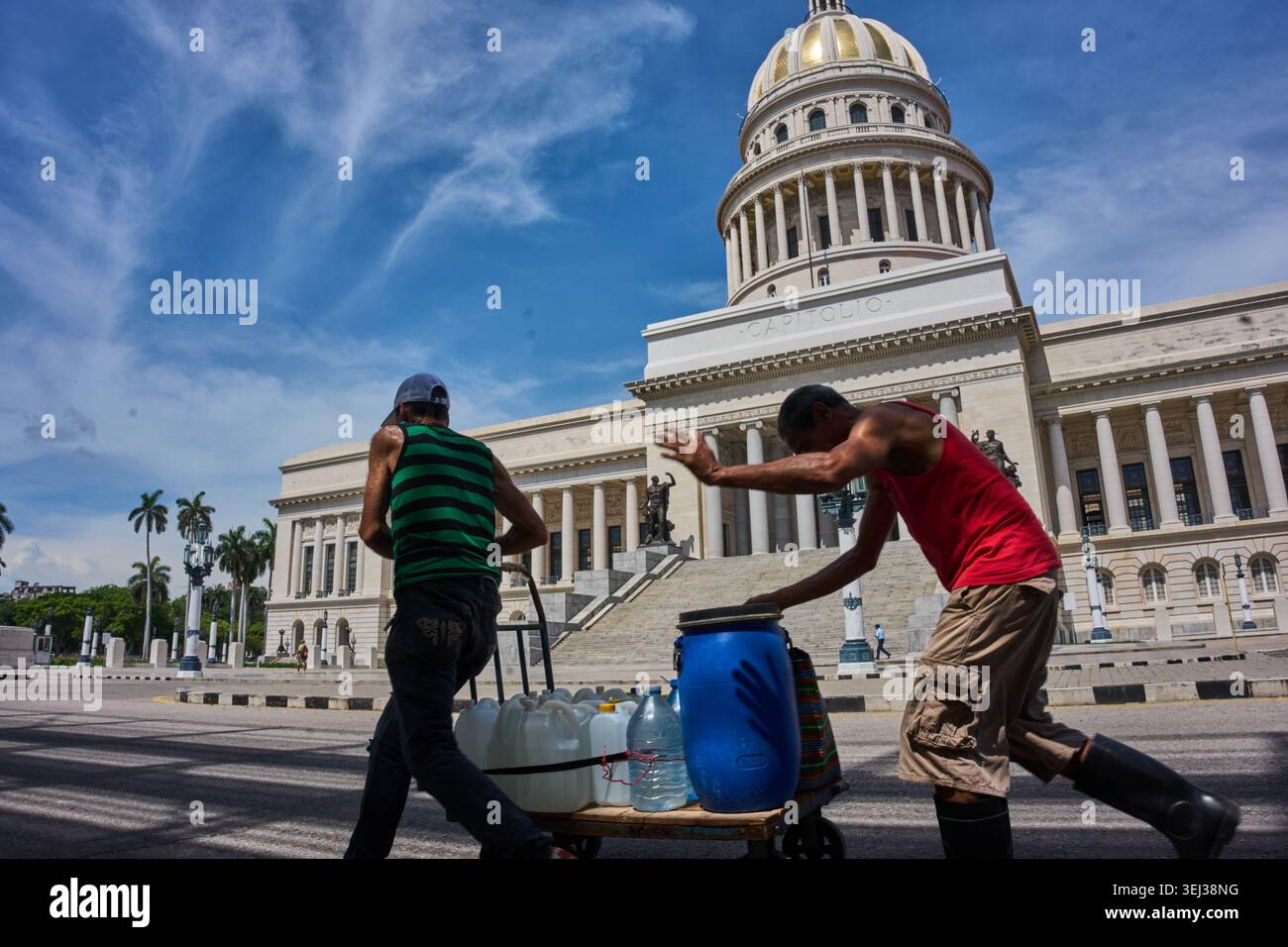 People carry containers of water past the Capitol in Havana, Wednesday ...