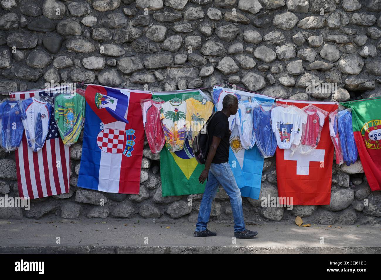 A pedestrian walks past flags and soccer jerseys for sale in a street ...