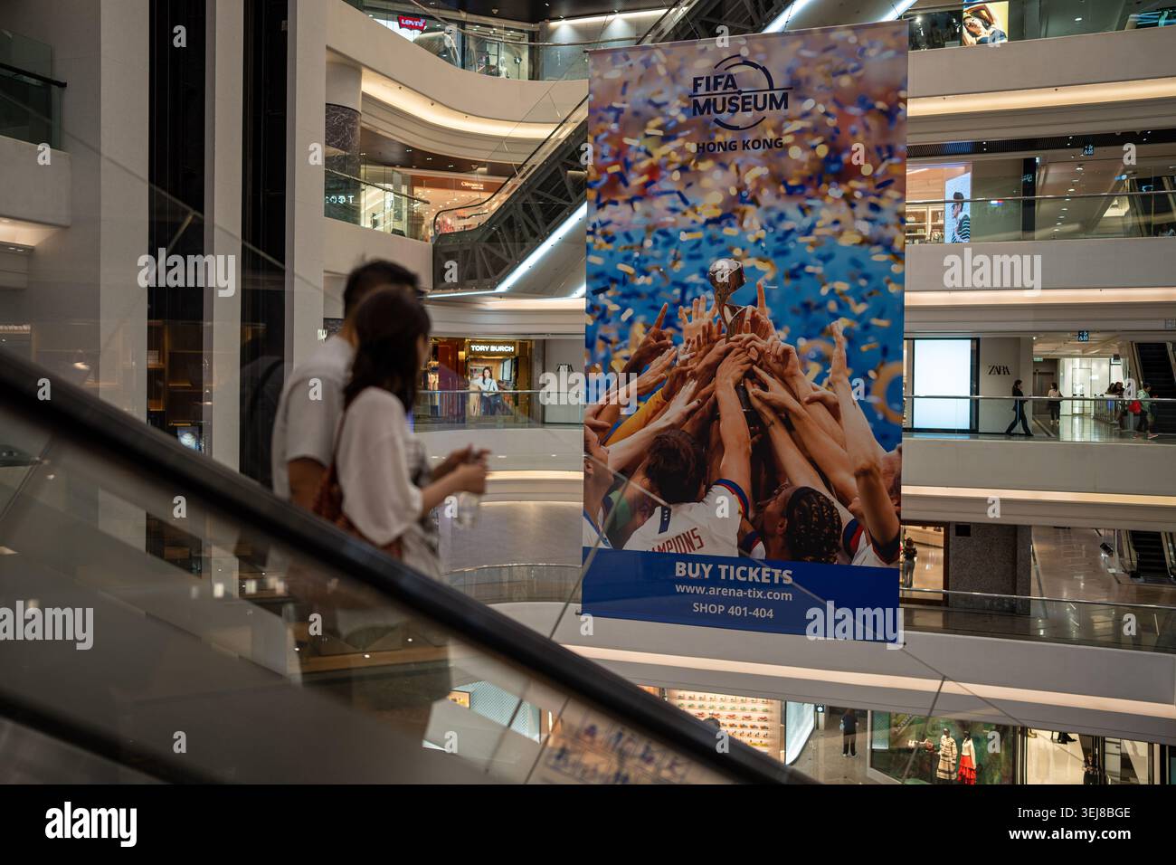 People riding on escalators pass a large banner for the FIFA Museum ...