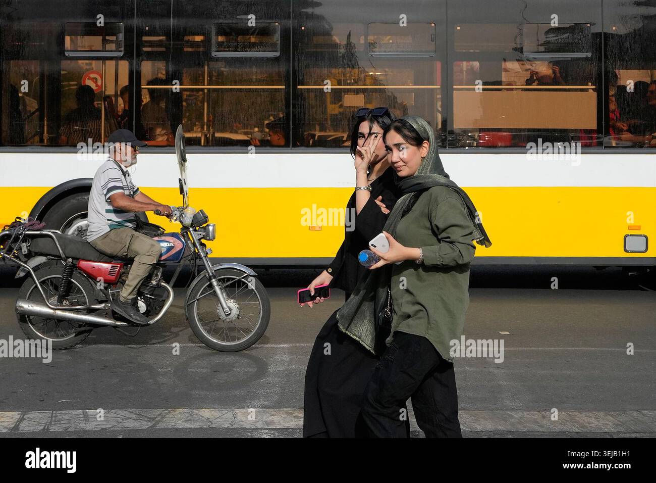 Women cross an intersection as one of them reacts to the camera while a ...