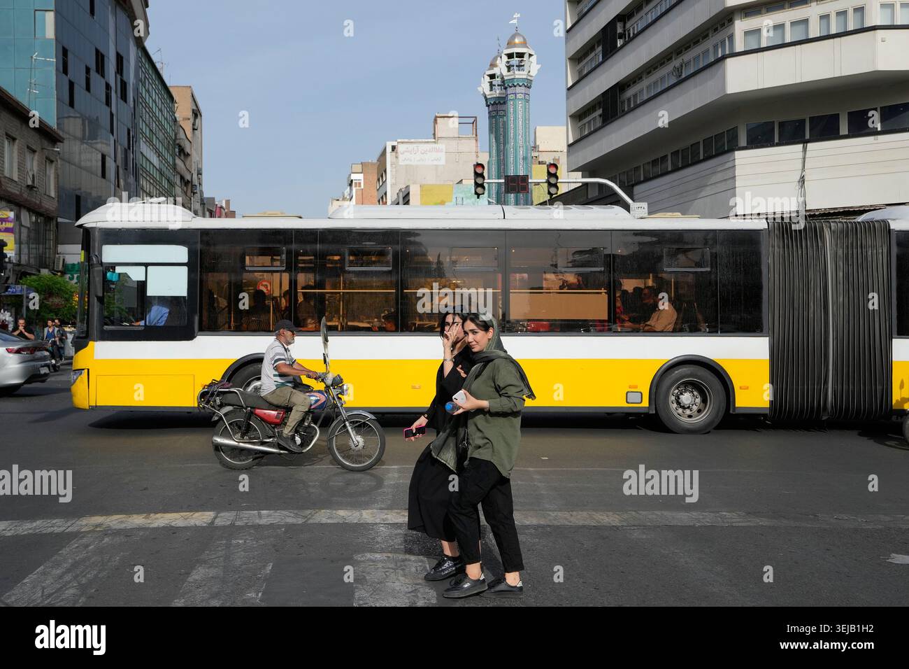 Women cross an intersection as one of them reacts to the camera while a ...