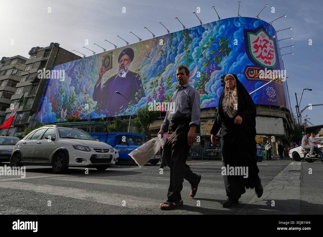 People cross an intersection in front of a billboard showing a portrait ...