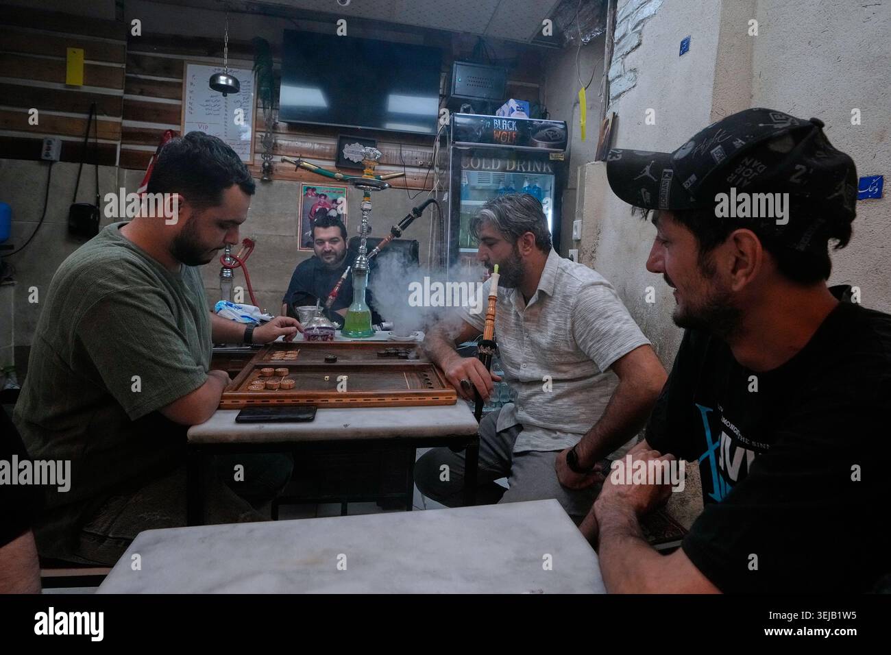 Two men play backgammon as one of them smokes water pipe at a tea house ...