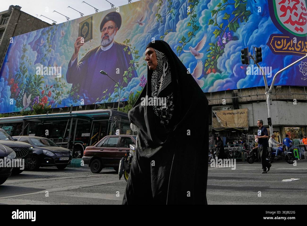 A woman crosses an intersection in front of a billboard showing a ...