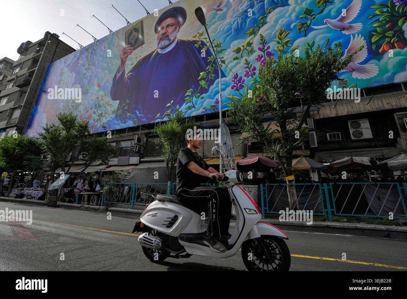 A motorbike drives past a billboard showing a portrait of the late ...