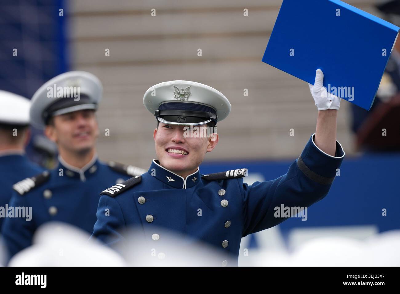 Air Force cadet waves a diploma during the United States Air Force ...