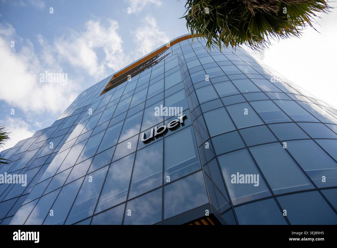 Exterior of modern glass building with Uber logo against blue sky and ...