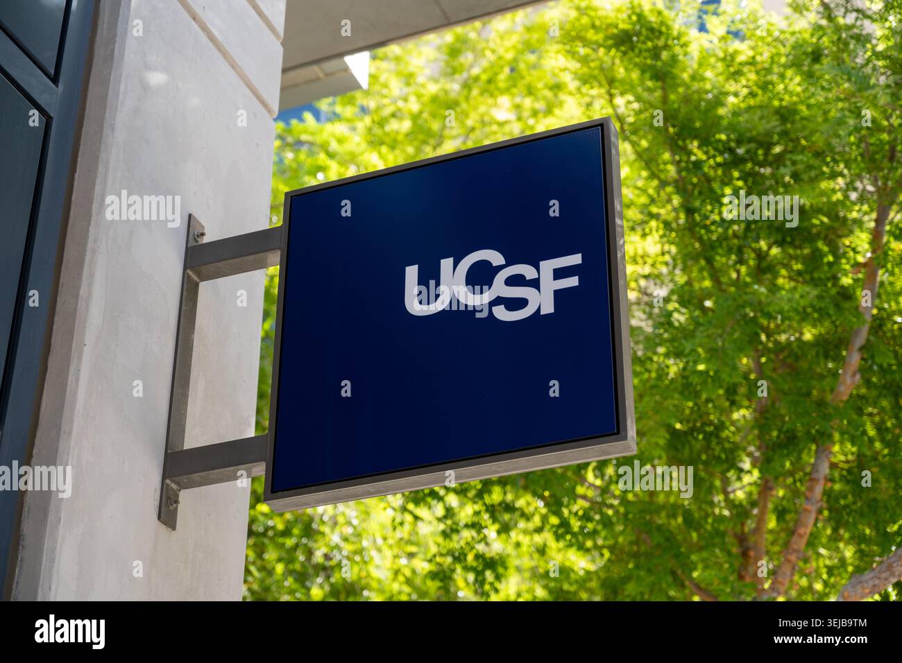 UCSF logo sign mounted on exterior of modern building with green trees ...