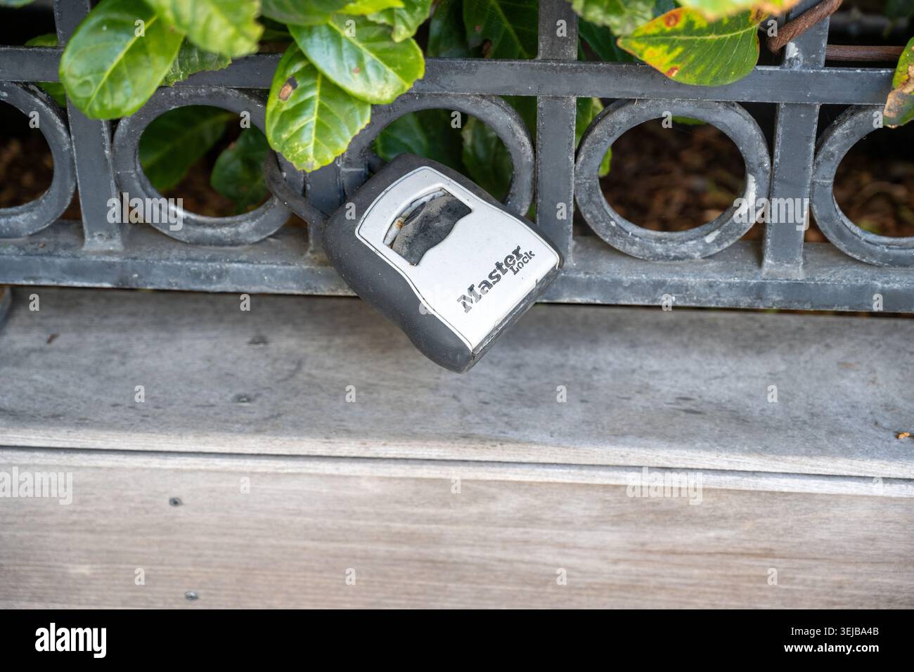 Close-up of Master Lock key lockbox attached to metal fence with green ...