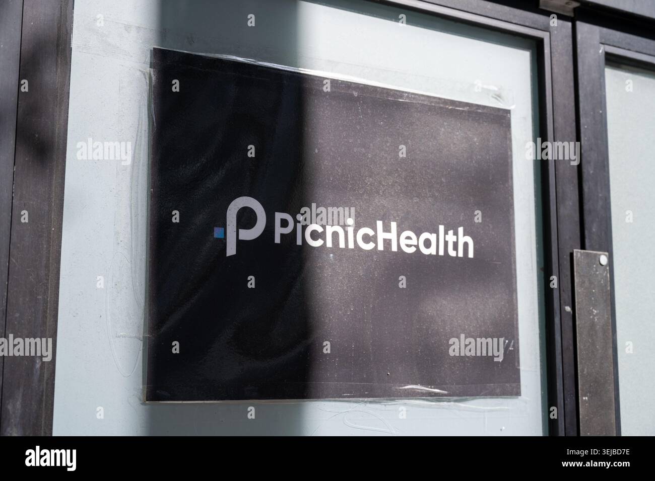 PicnicHealth sign on exterior door of a building in sunlight and shadow ...