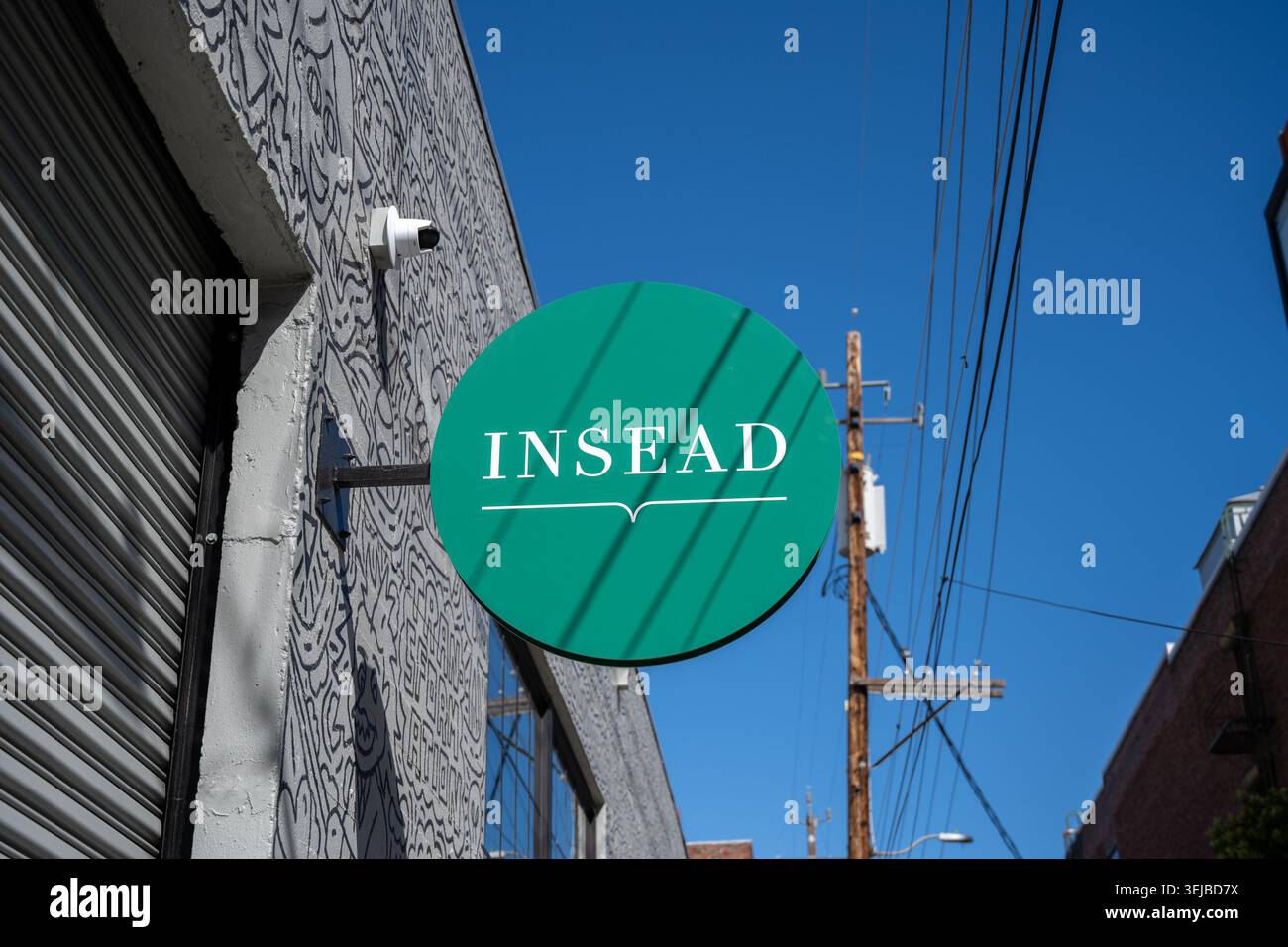 Round green INSEAD sign hanging on patterned gray building wall in ...