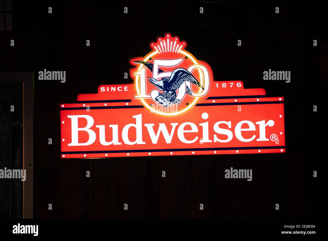 Illuminated Budweiser 150th anniversary sign on a dark interior wall ...