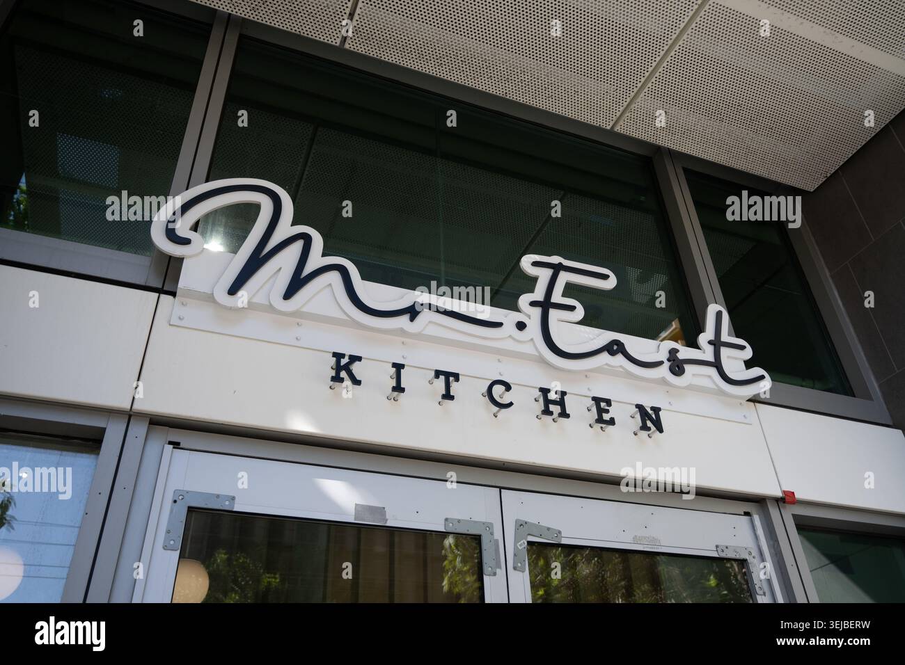 Exterior sign for Mr. East Kitchen restaurant on modern glass building ...