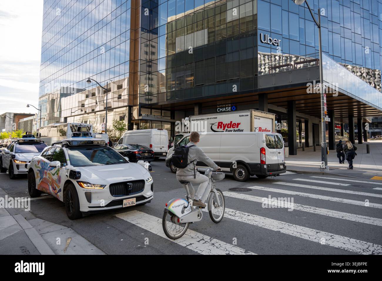 Cyclist on Google-branded bike crossing busy city street with self ...