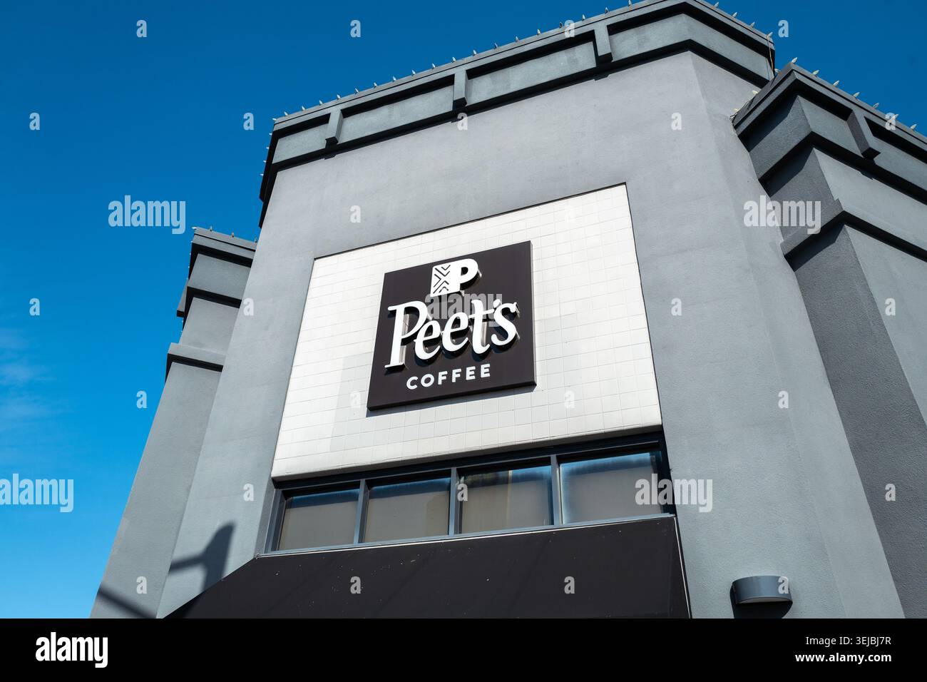 Peets Coffee logo on exterior of gray building against clear blue sky ...