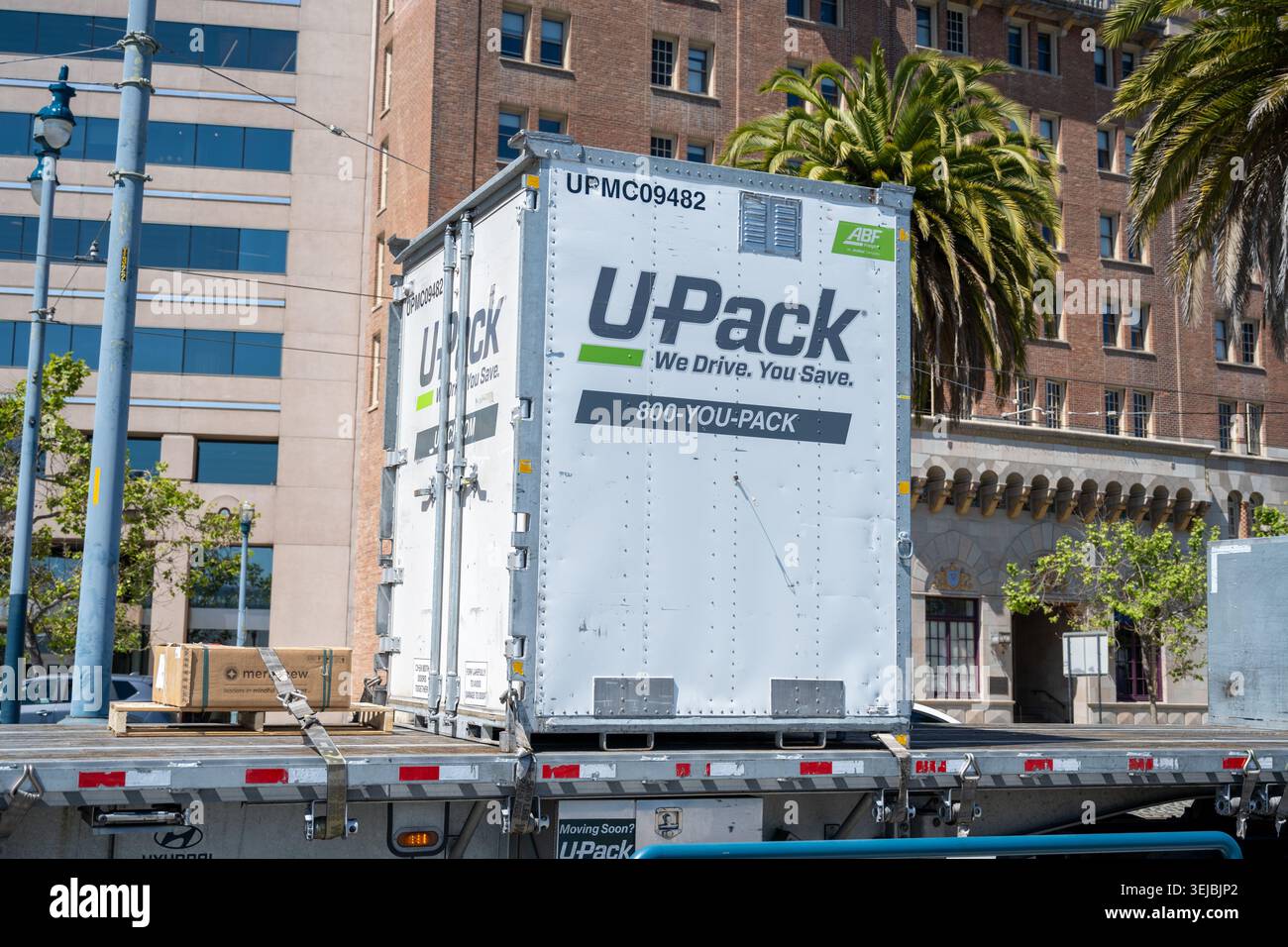 UPack moving container on flatbed truck in front of urban buildings and ...