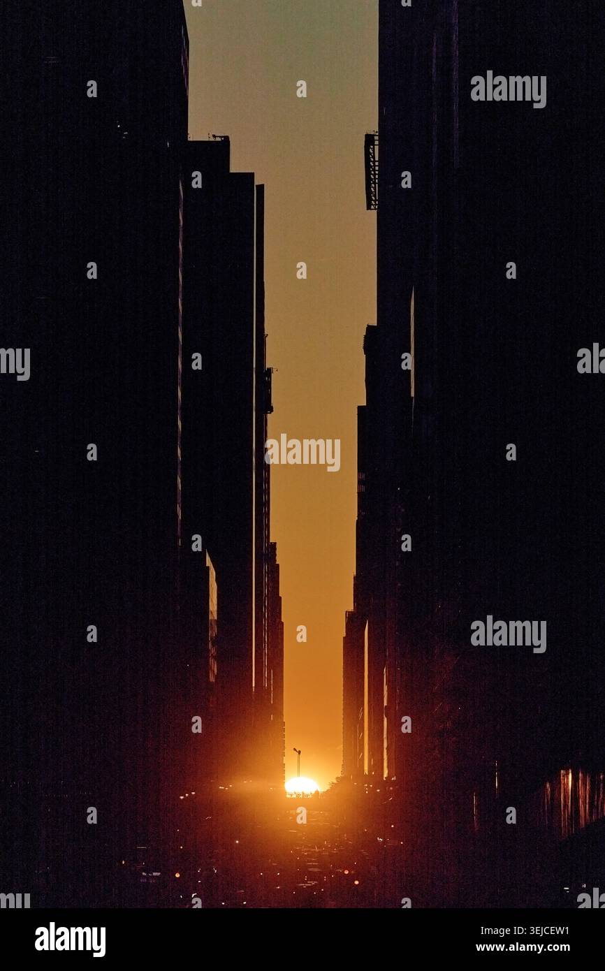 The setting sun is framed between buildings during Manhattanhenge along ...