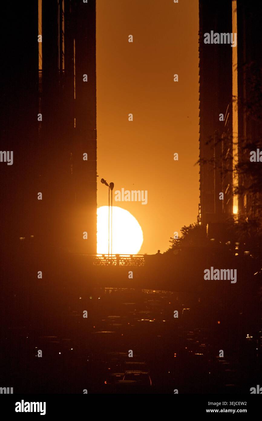 The setting sun is framed between buildings during Manhattanhenge along ...