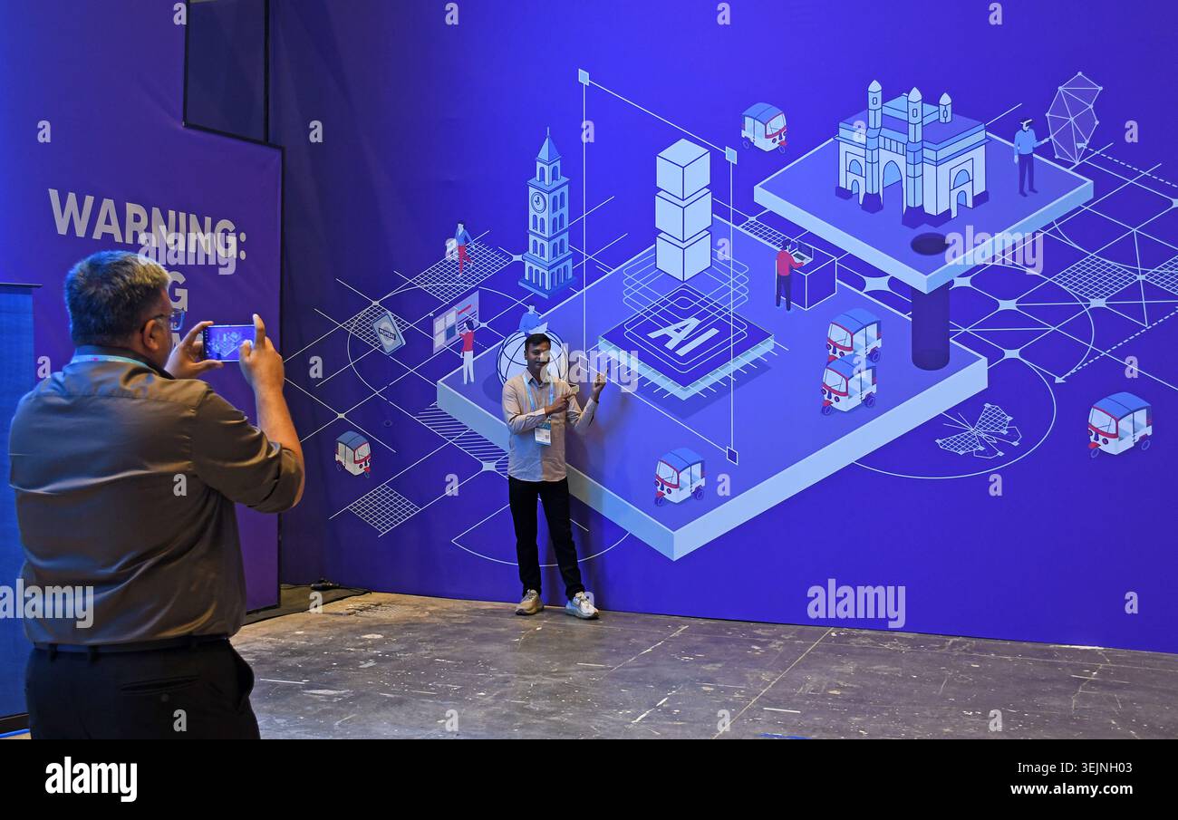 A visitor (R) poses for a photo near the AI poster at Mumbai Tech Week ...