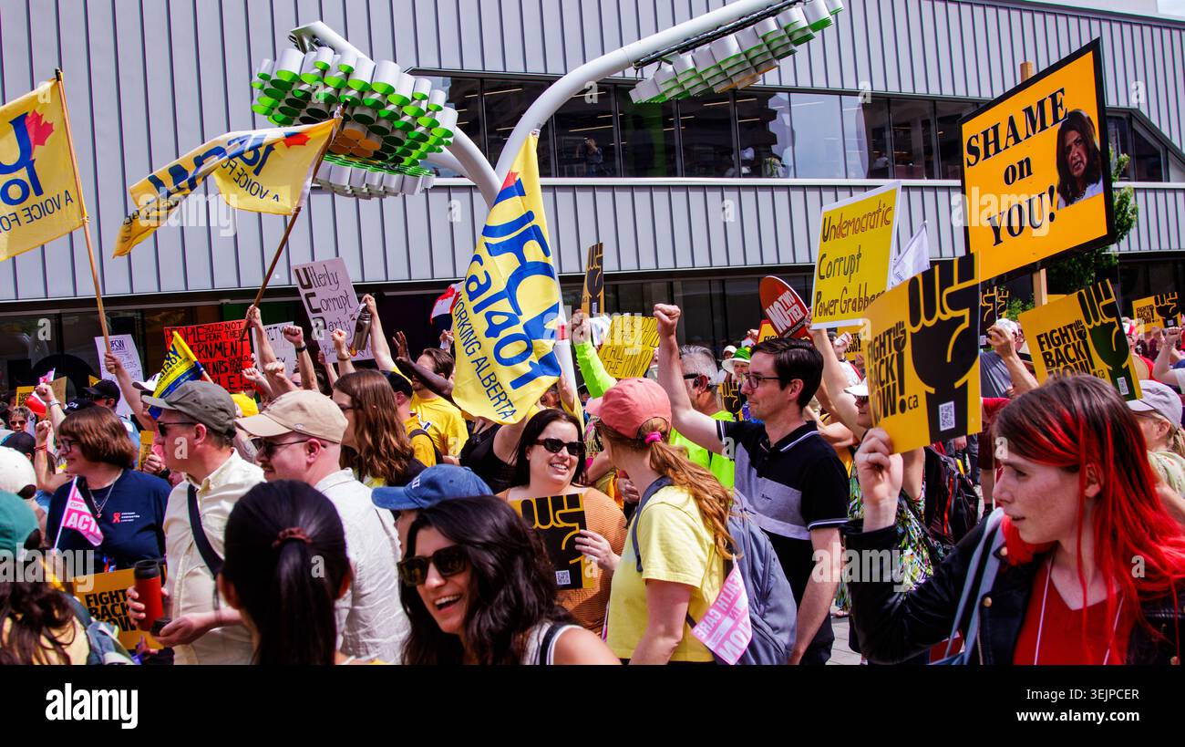 A crowd of protesters marches with signs and flags through the streets ...