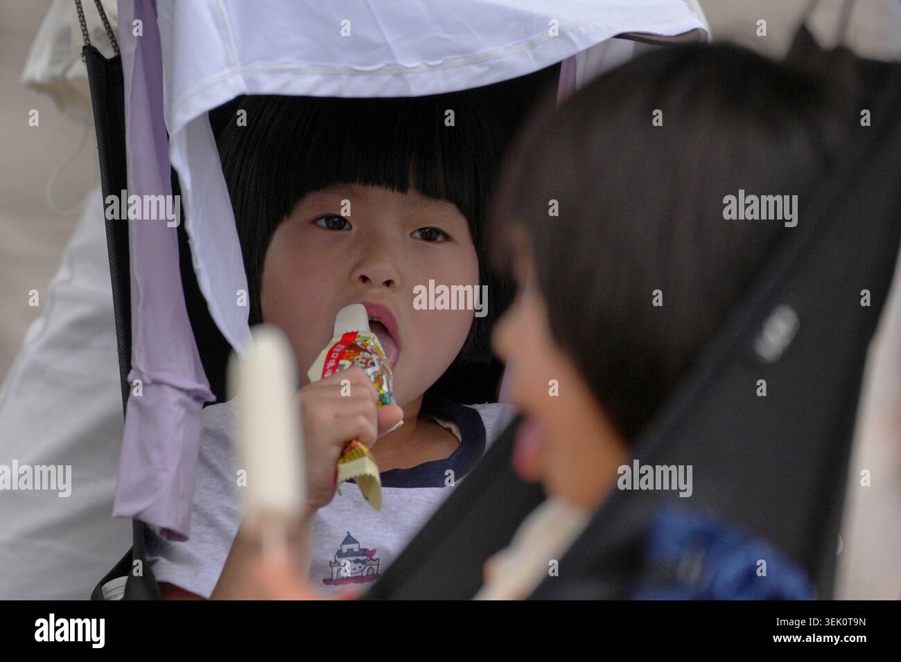 Children eat ice-cream on their strollers on a sweltering day, in ...