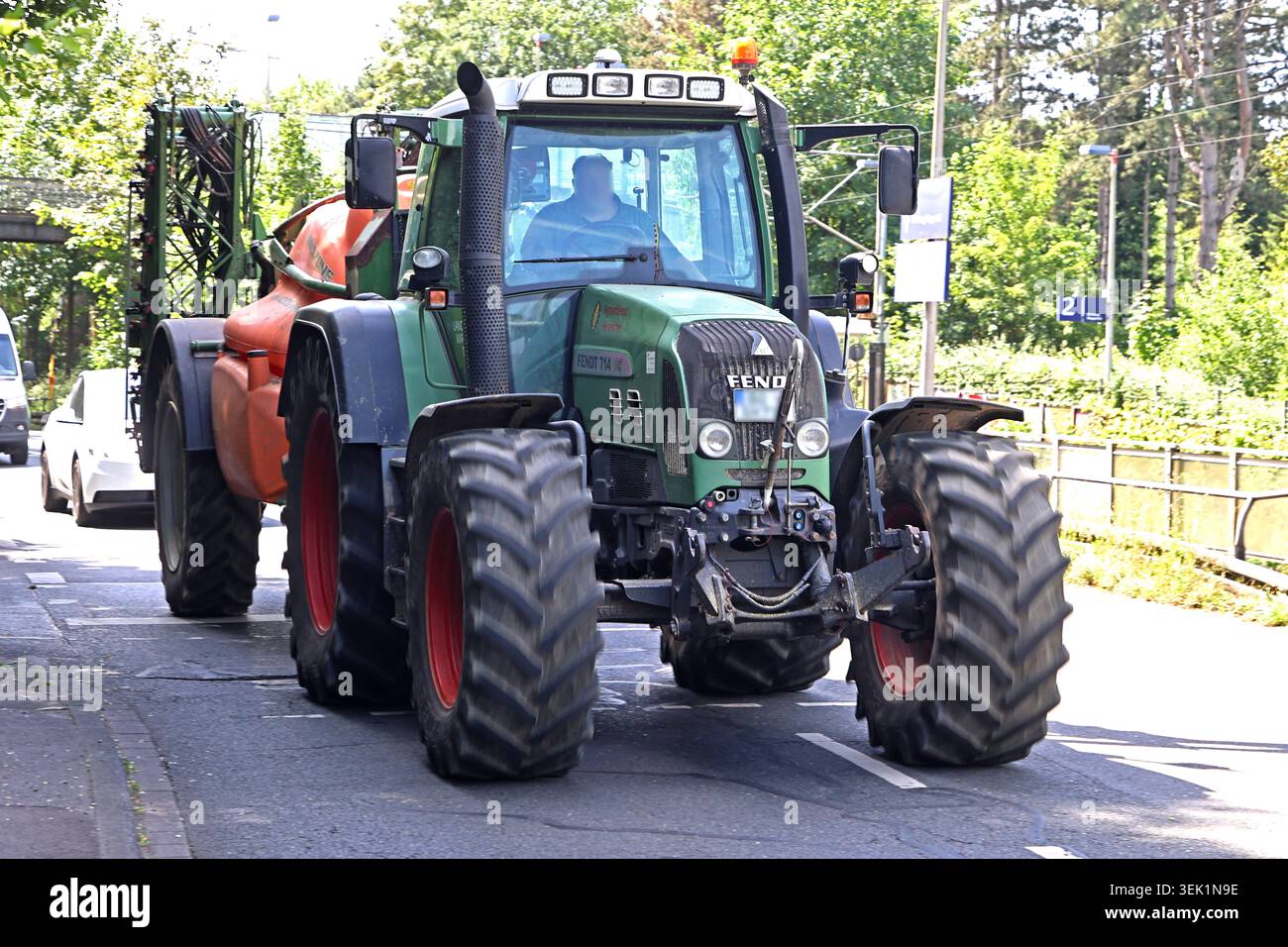 Landarbeit im späten Frühling Ein Traktor befährt eine Landstraße weit ...