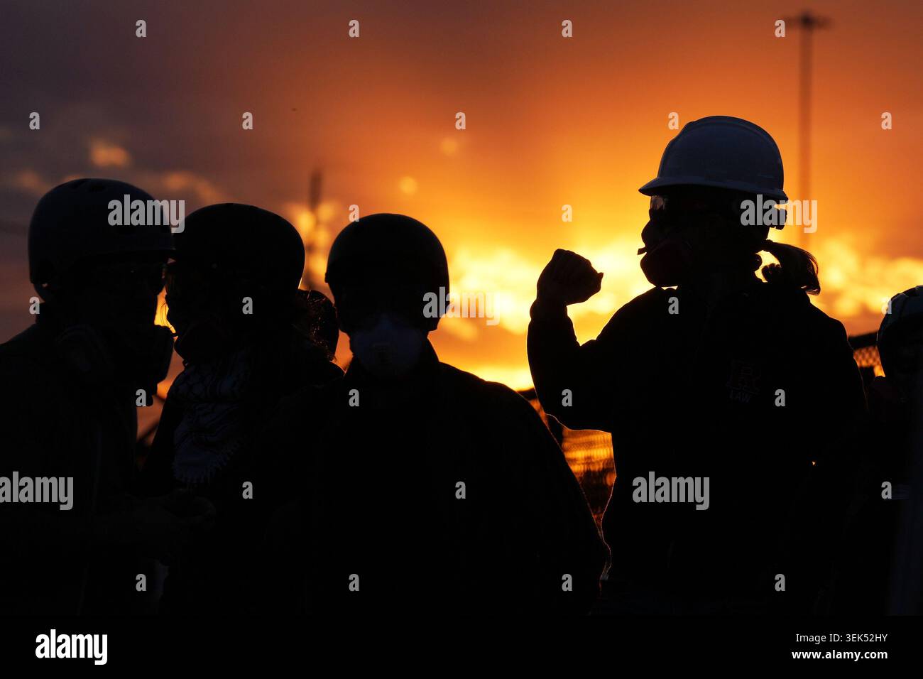 Protesters are silhouetted against the sunset outside Delaney Hall ...