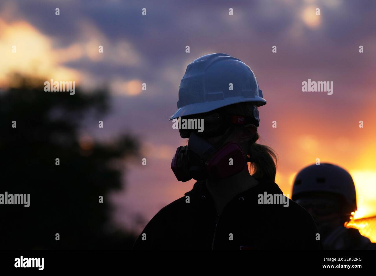 Protesters are silhouetted against the sunset outside Delaney Hall ...