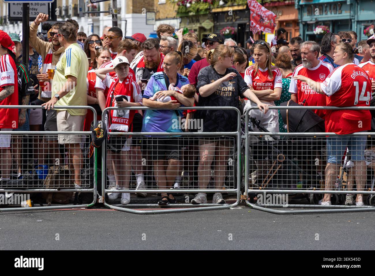 Arsenal fans celebrate on the side of the street as they wait for the ...