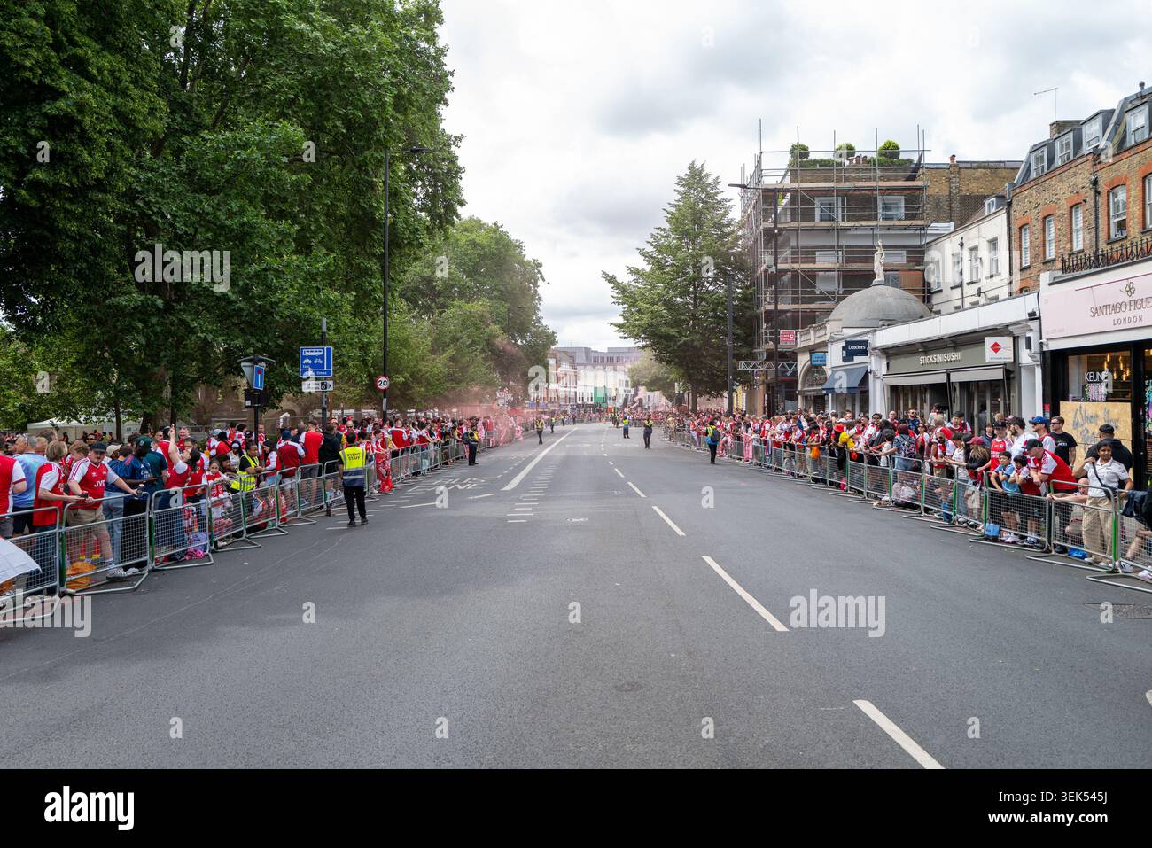 Arsenal fans celebrate on the side of the street as they wait for the ...