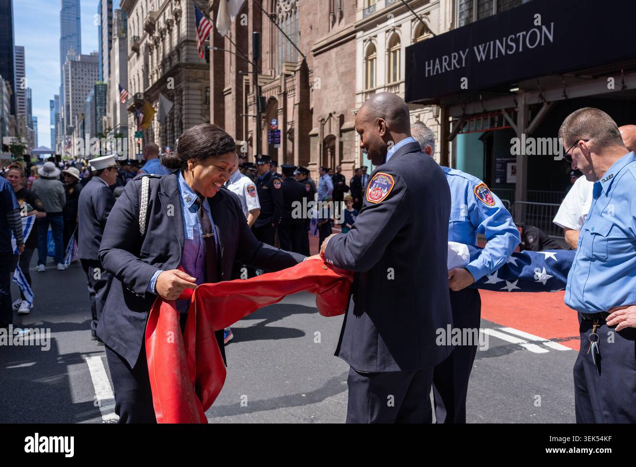 Firefighters in uniform handle a red cloth and a folded American flag ...