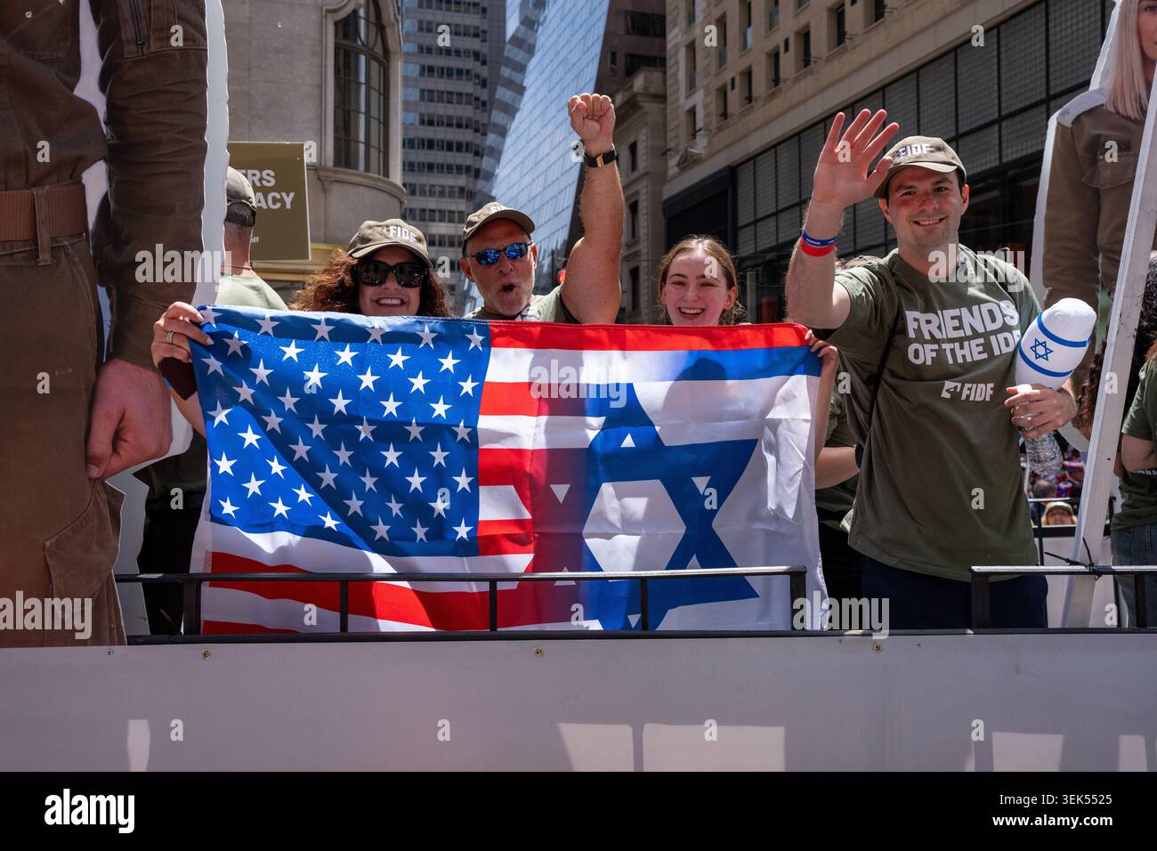 Four smiling people hold a combined American and Israeli flag during a ...
