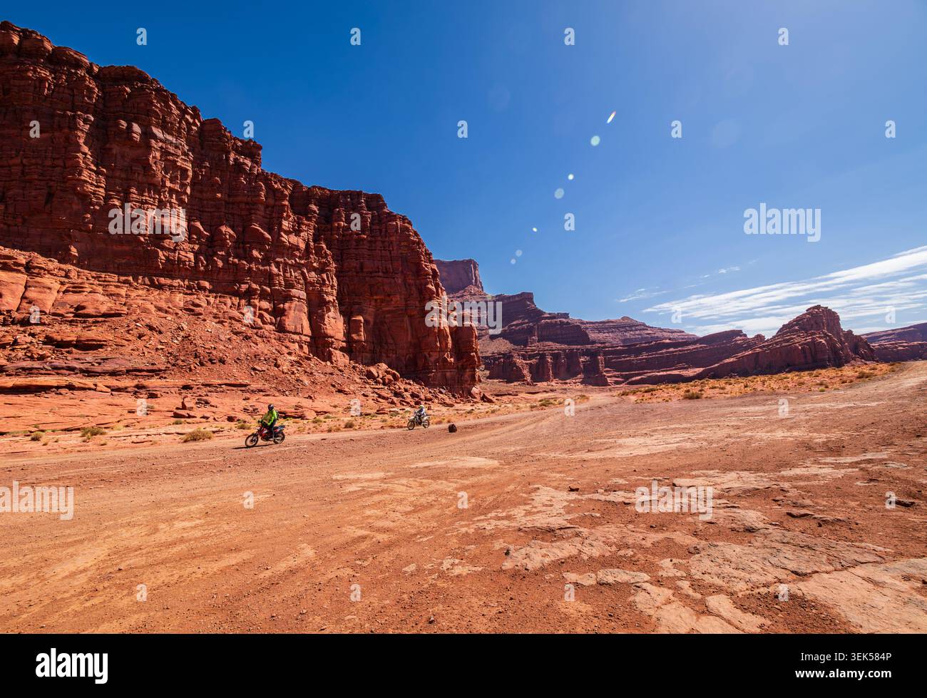 Moab, Utah May 15 2026 Two cyclists pass towering red sandstone cliffs ...