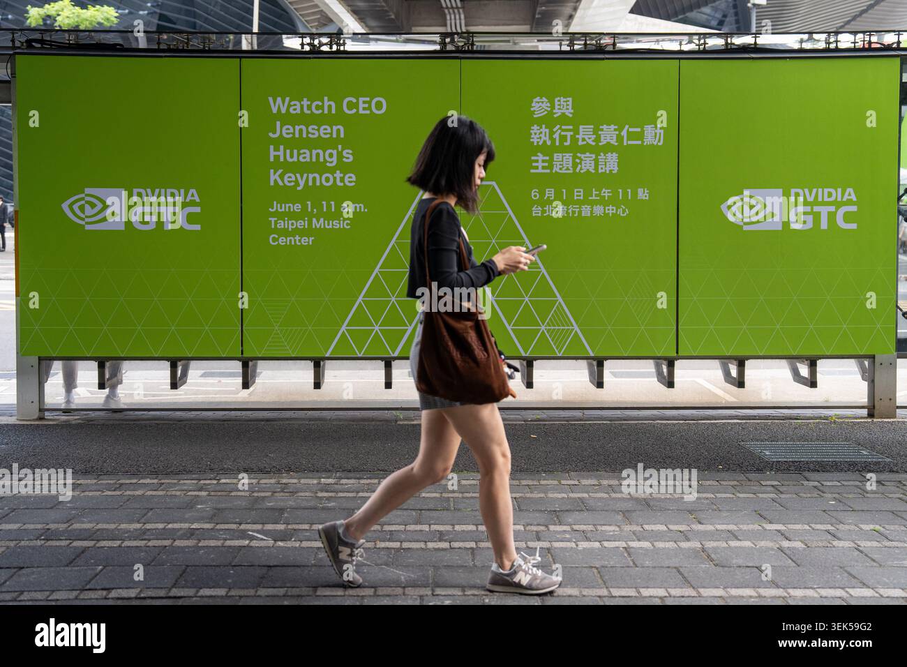 A woman walks pass a banner near the venue where Nvidia CEO Jensen ...