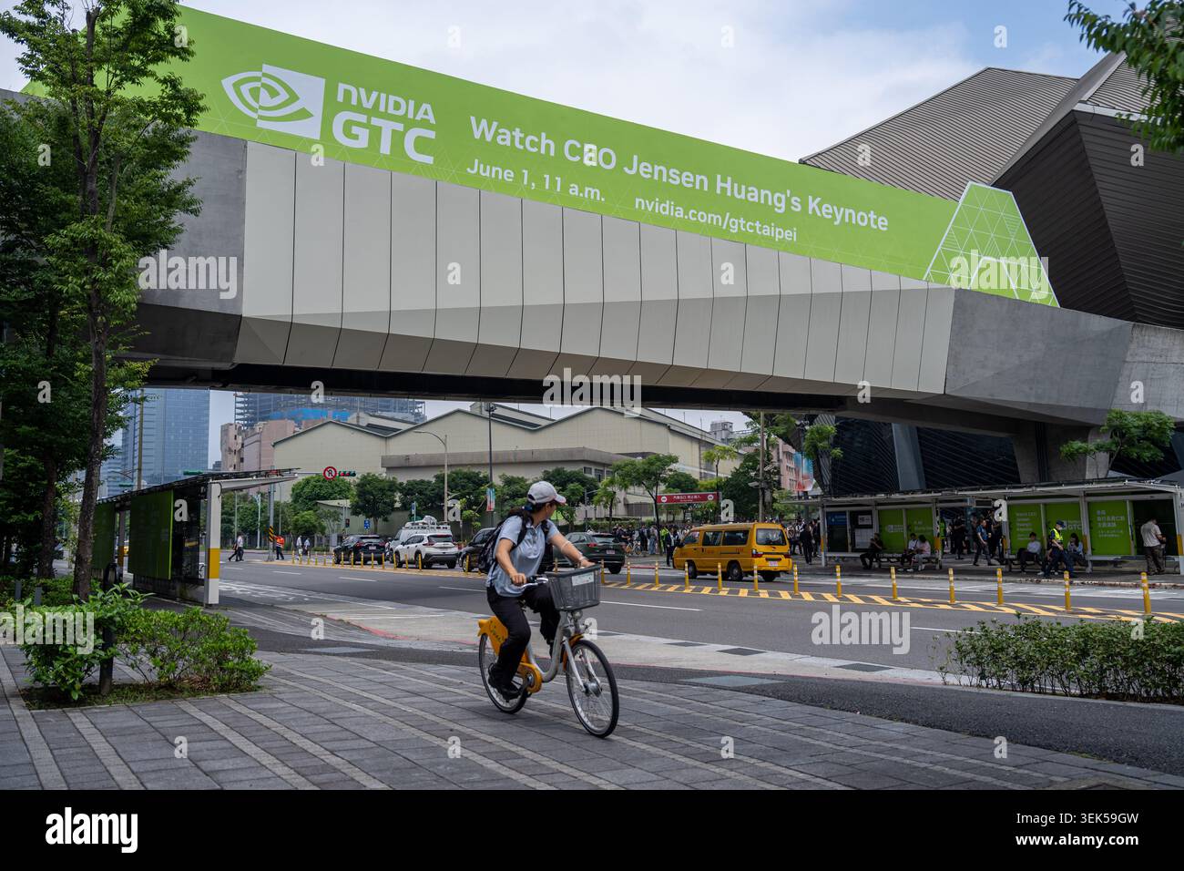 A cyclist cycling pass a large banner outside the venue where Nvidia ...